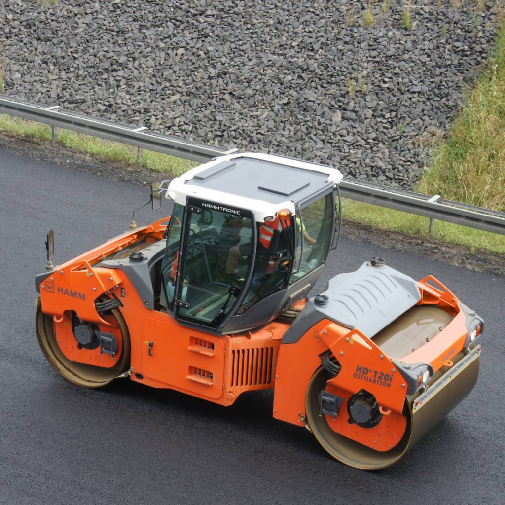 A HAMM HD+ 120i OV tandem roller compacting the surface course of a ...